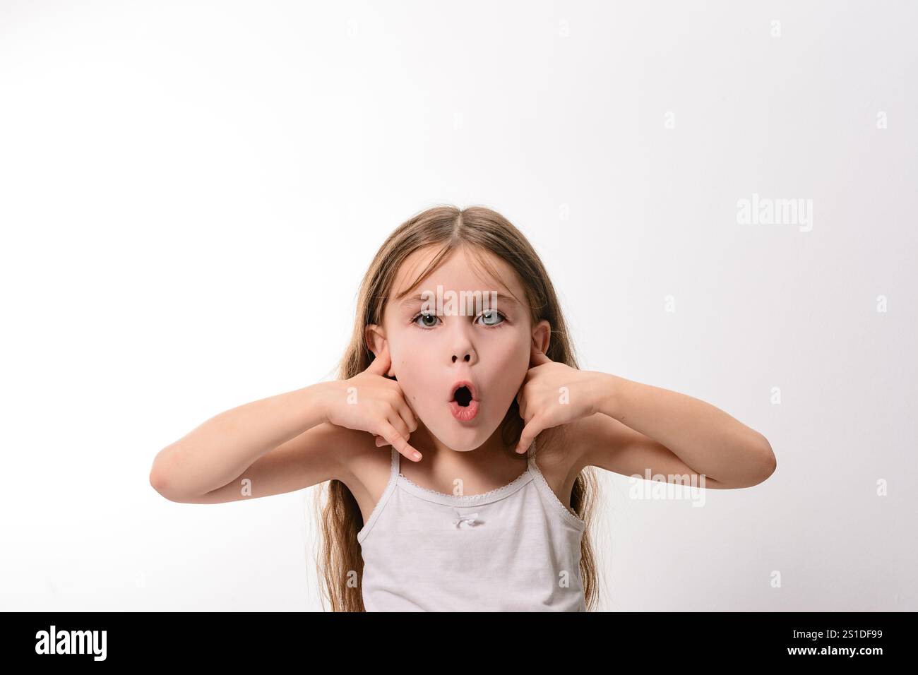 A young girl with long brown hair makes a comical expression. She's ...