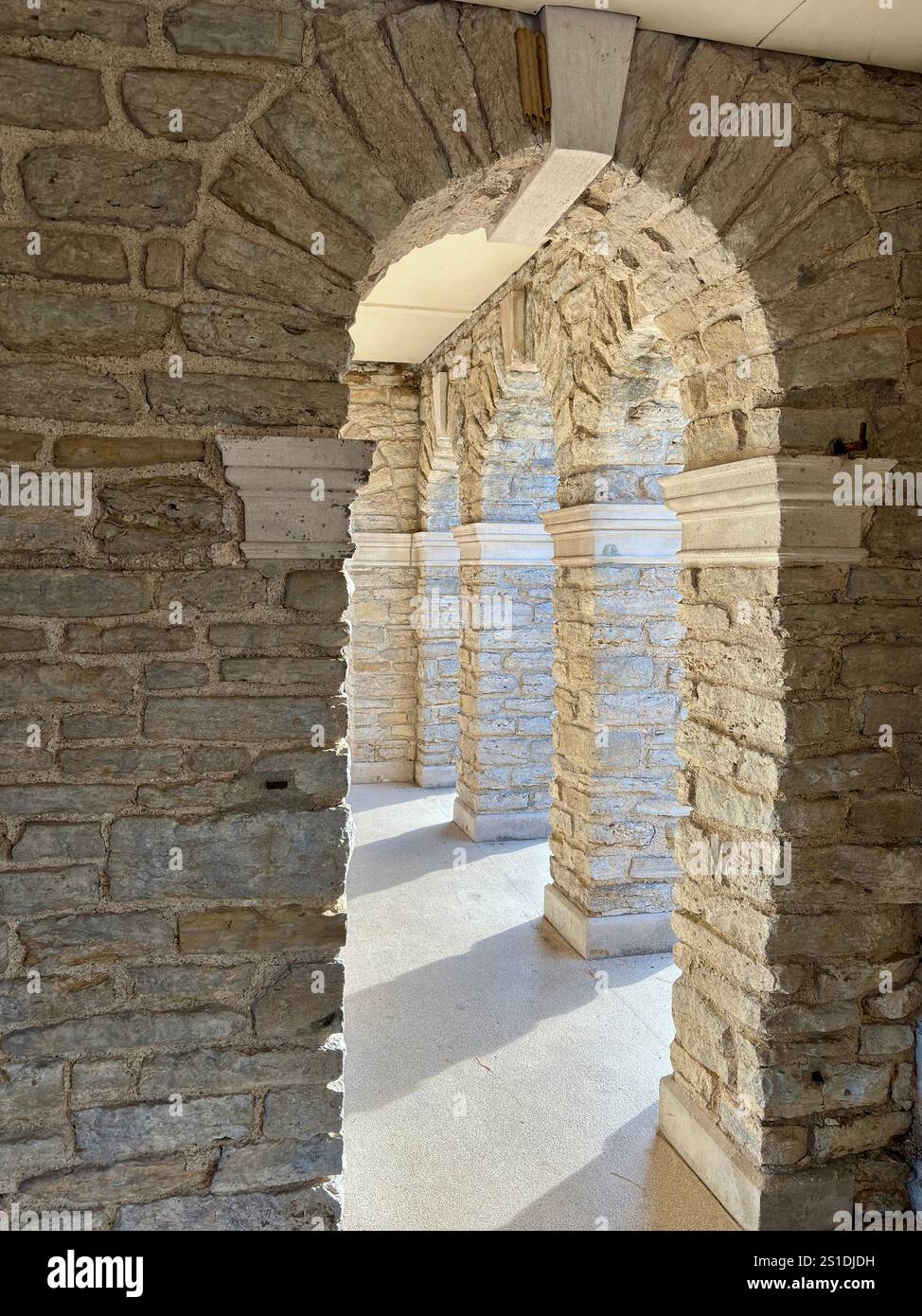 Sunlit stone arches with pathway with textured surfaces and shadows ...
