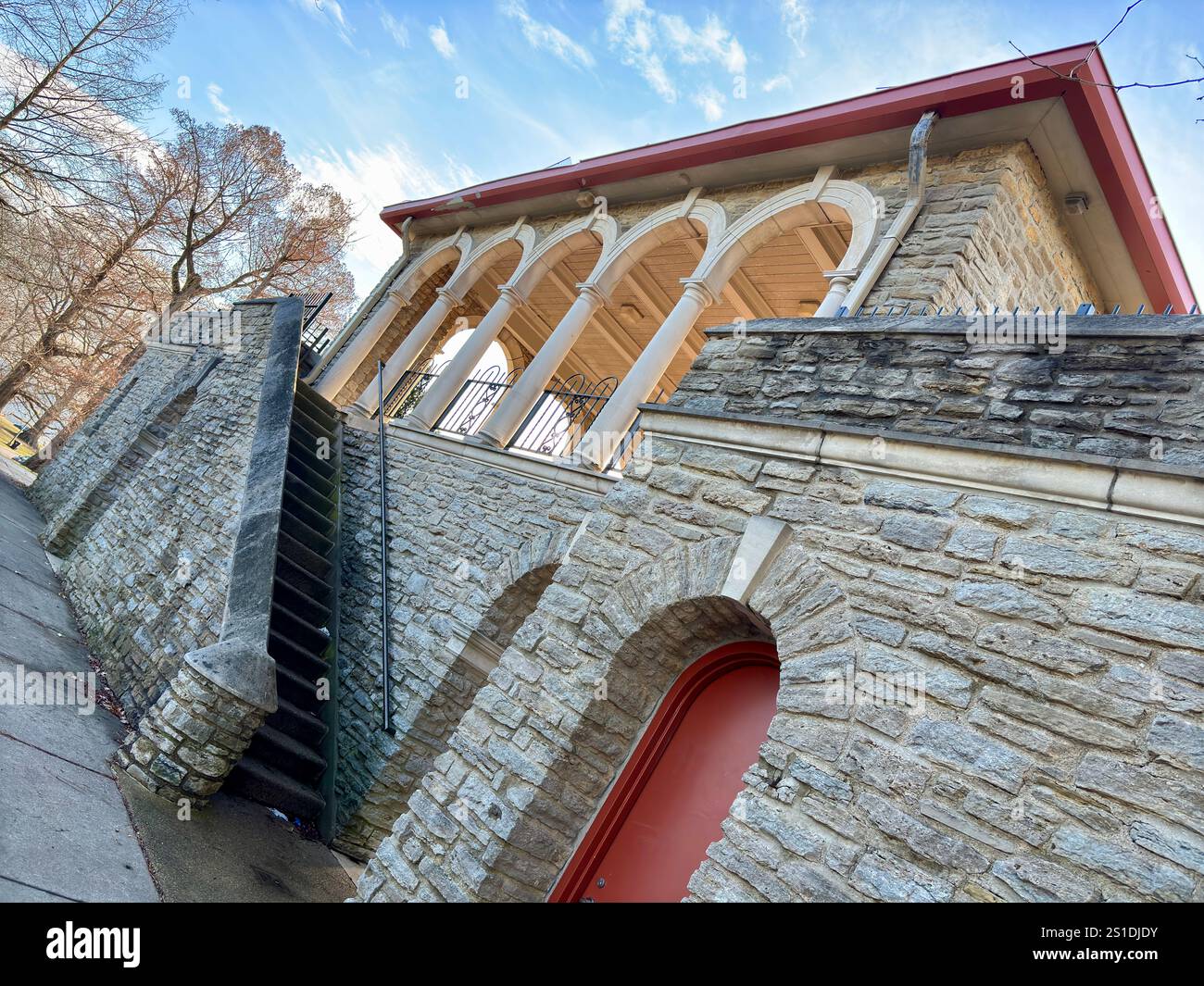 Historic stone building with arched columns, staircase, red door Stock ...