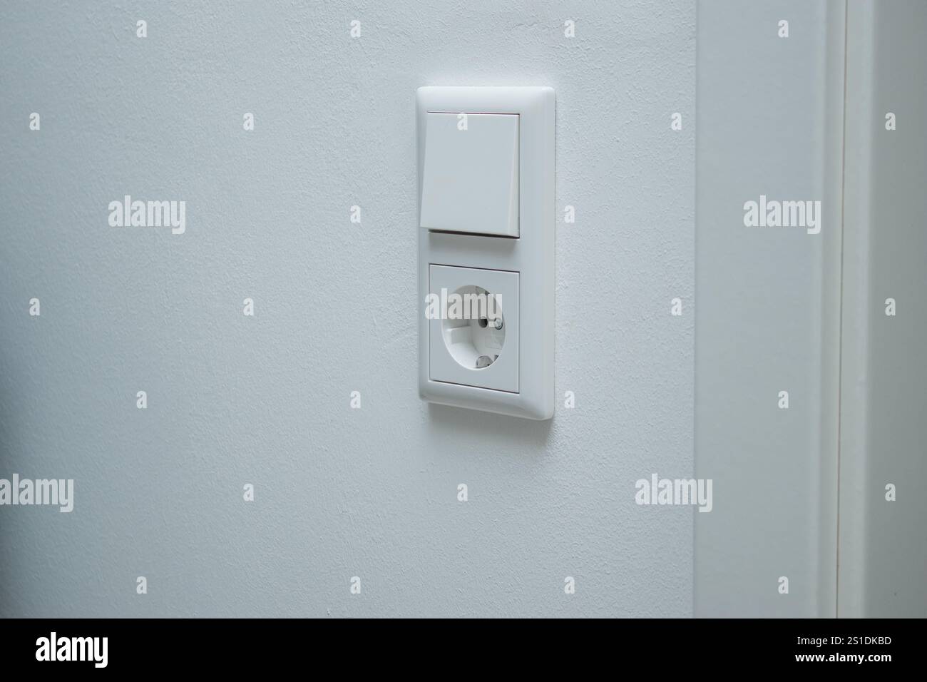 Close up of a double electric light switch and a socket on white wall ...