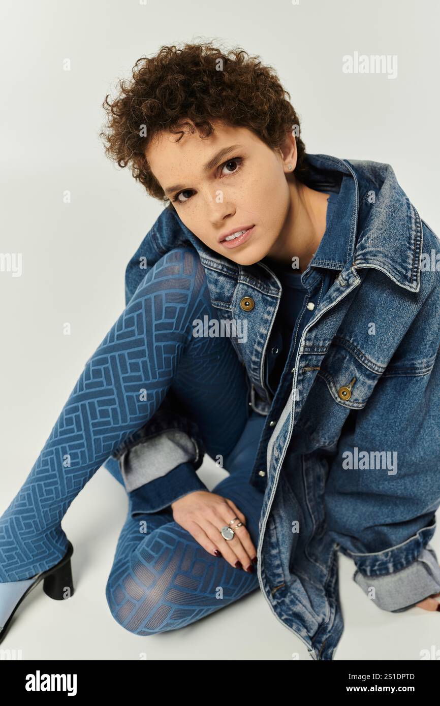 A striking young woman poses gracefully in a denim outfit, highlighting ...