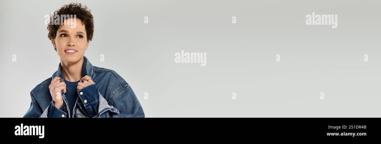 Confident young woman smiles in a trendy denim jacket against a light ...