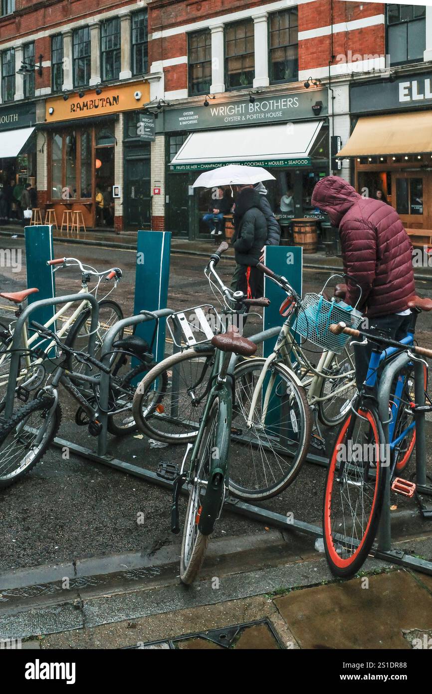 Locked bicycles in a cycle rack in a street in Southwark in a rainy ...