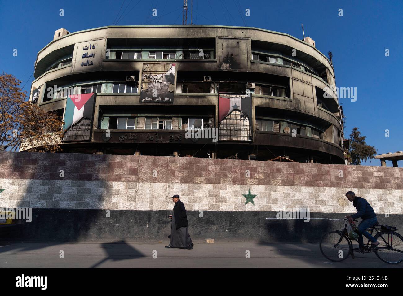 People walk past a security building that belonged to the Assad regime ...