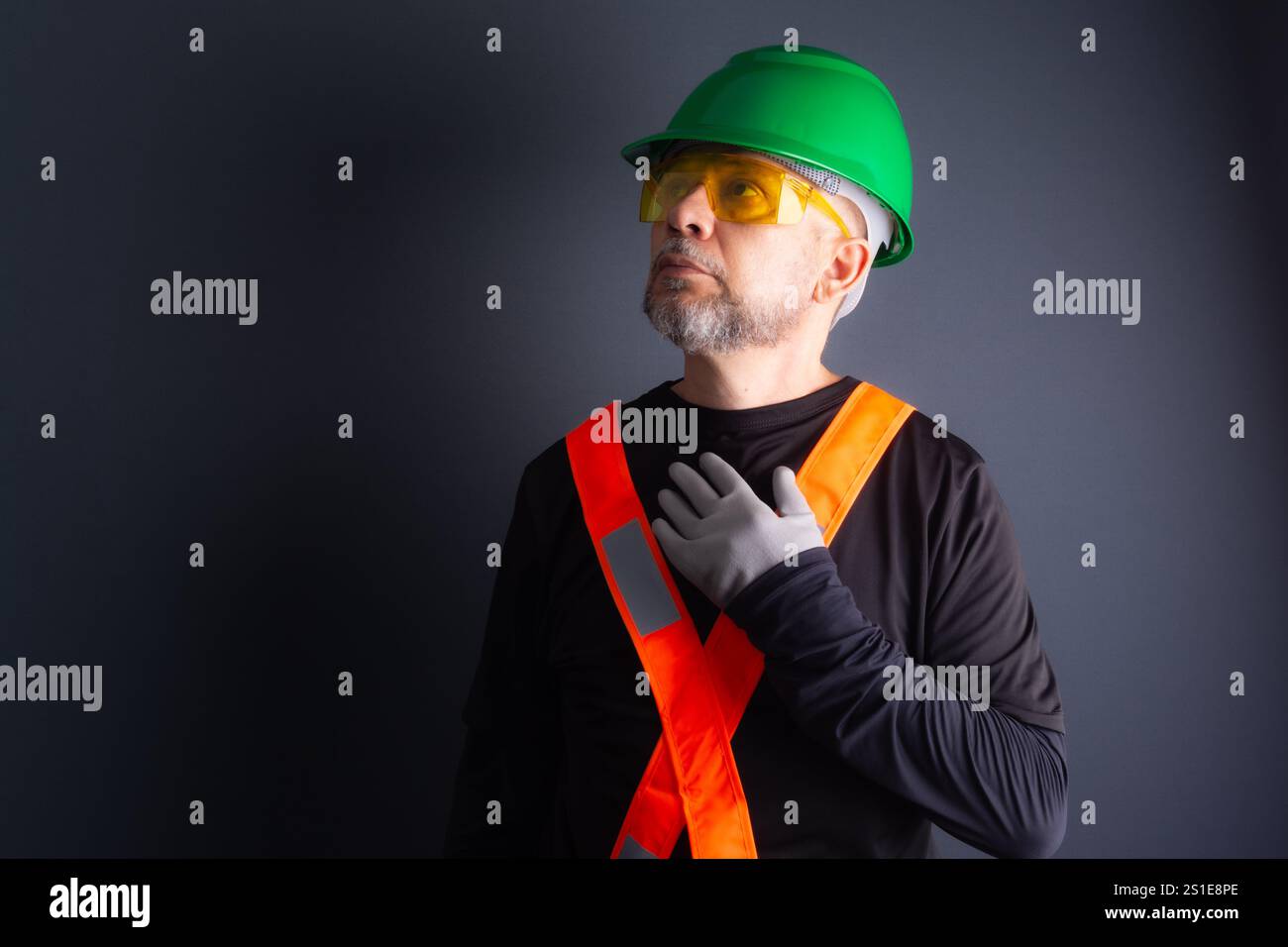 Photo of a civil worker wearing a green helmet, reflective vest and ...