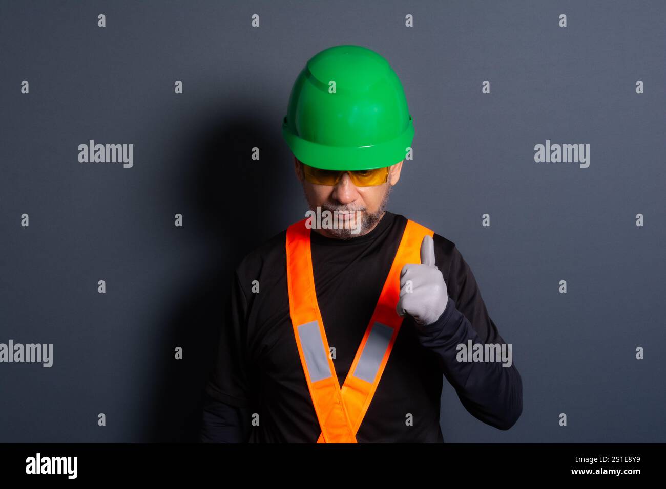 A civil worker wearing green helmet, reflective vest and protective ...