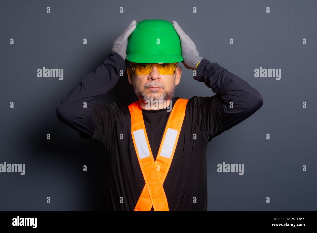 Photo of a civil worker wearing a green hard hat, reflective vest and ...