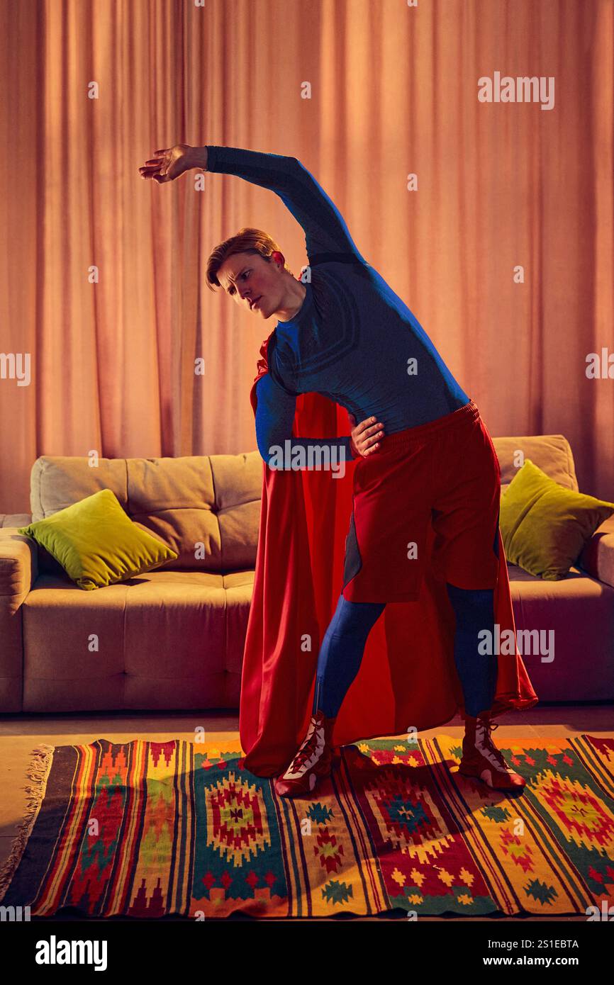 Superhero costume-wearing man bends sideways, performing a focused ...