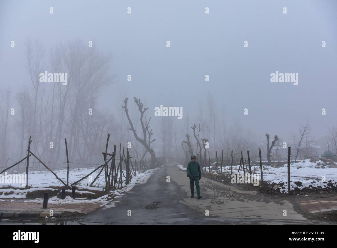 Srinagar, India. 03rd Jan, 2025. A man walks along the road during ...
