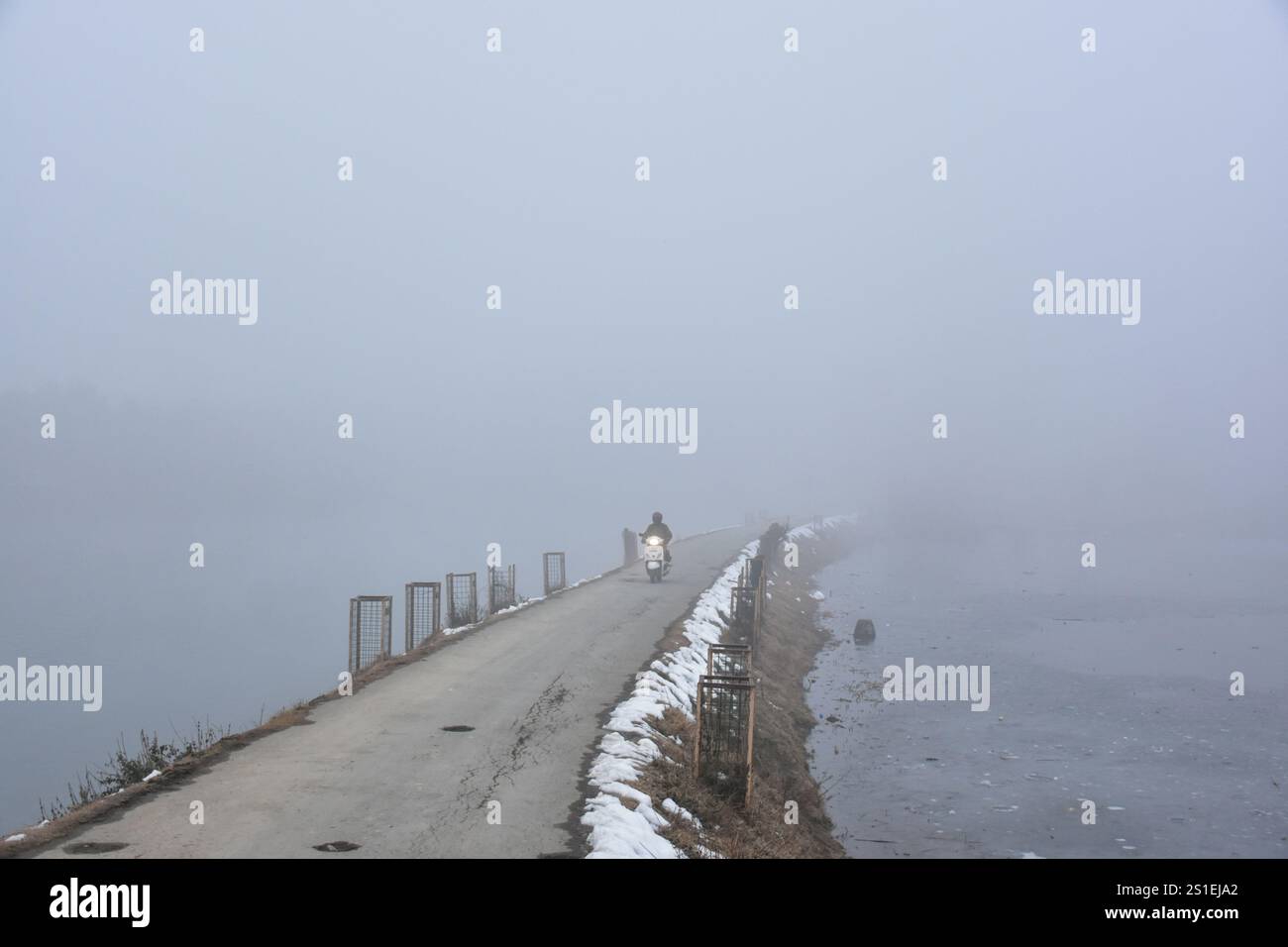 Srinagar, India. 03rd Jan, 2025. A man rides his scooter through the ...