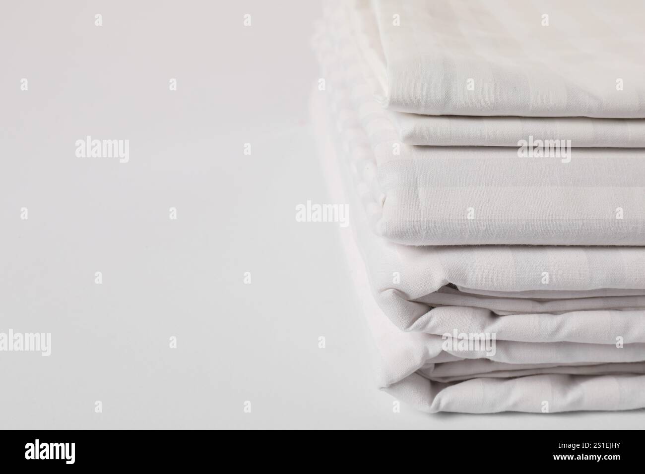 Stacked clean bed linens on white background Stock Photo - Alamy