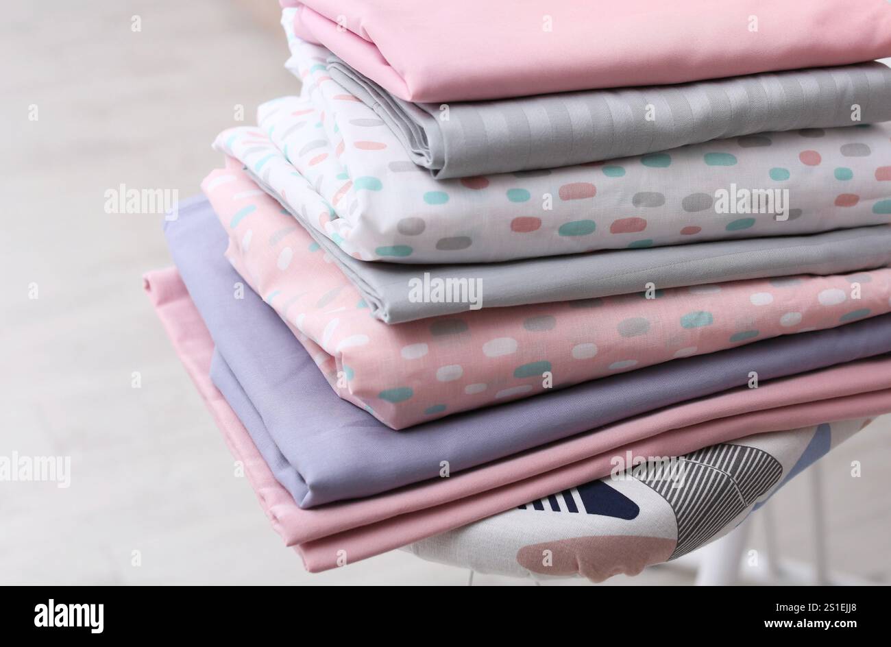Stack of clean bed linens on ironing board in room Stock Photo - Alamy