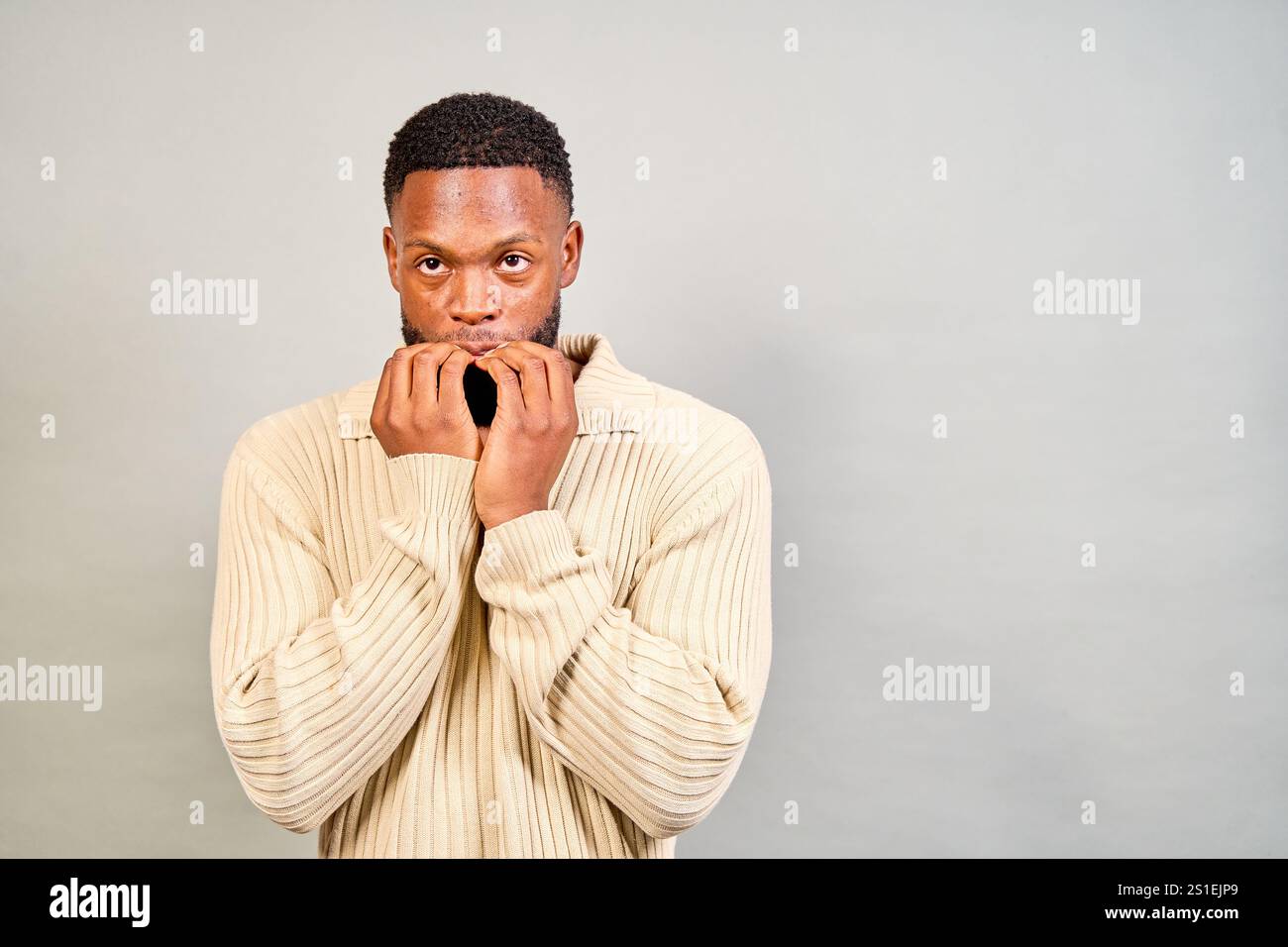 Young man biting his fingernails while feeling worried and anxious ...