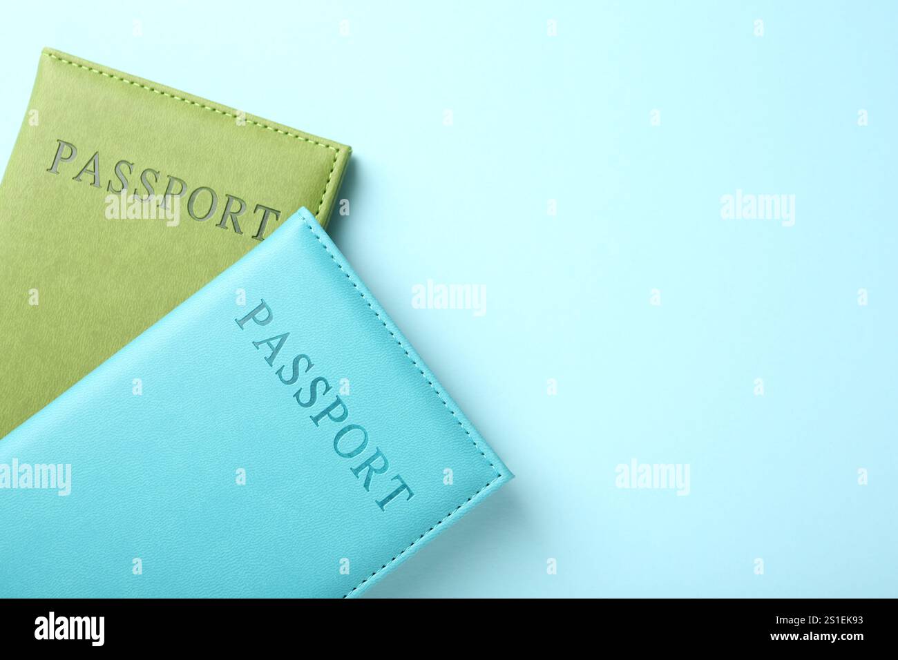 Passports in color covers on light blue background, top view. Space for ...