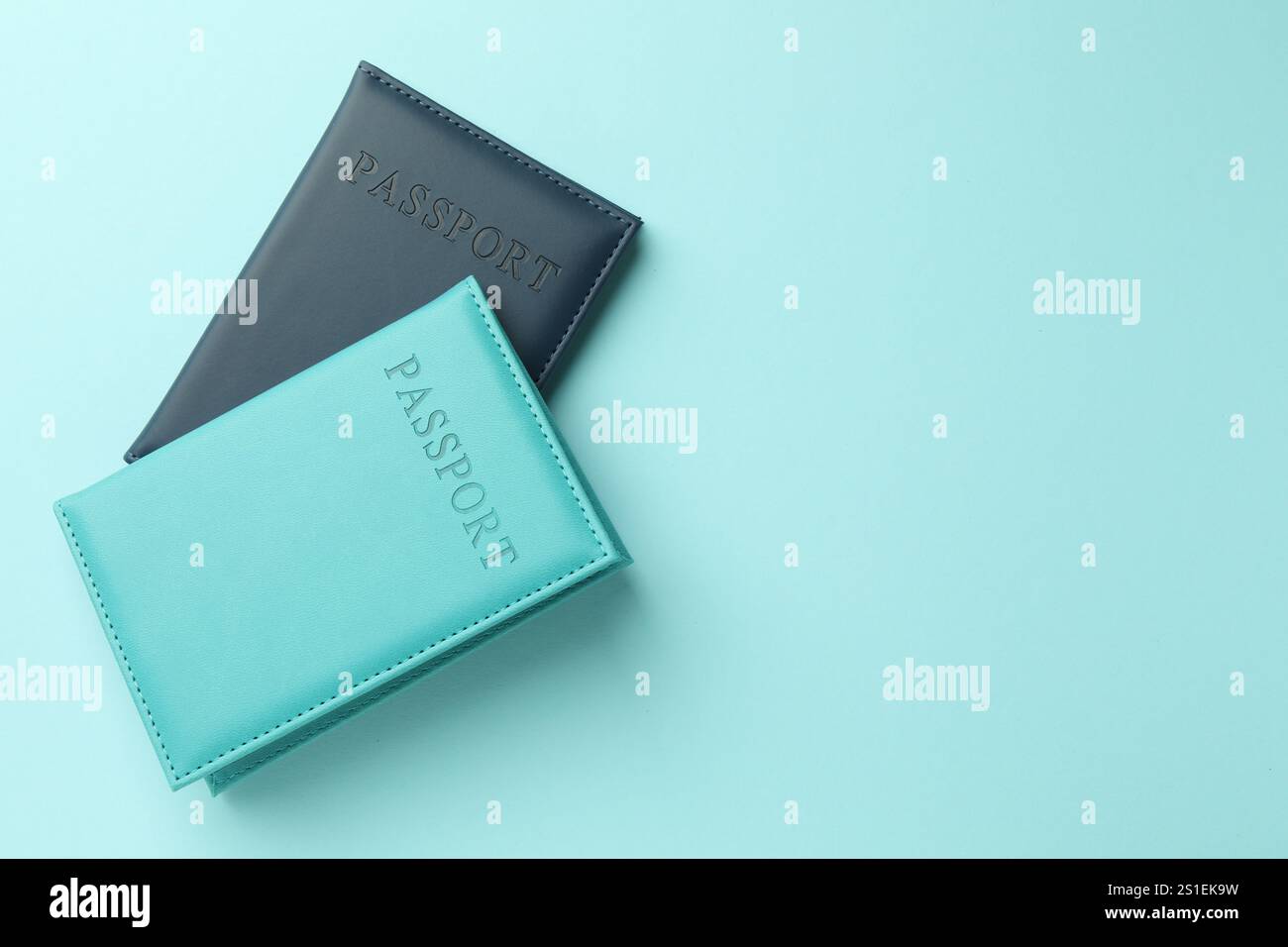 Passports in color covers on light blue background, top view. Space for ...