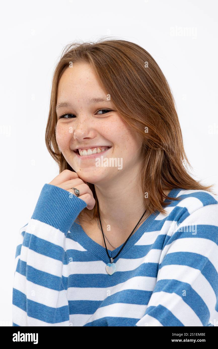 A cheerful teenager in a striped sweater smiles brightly against a pure ...