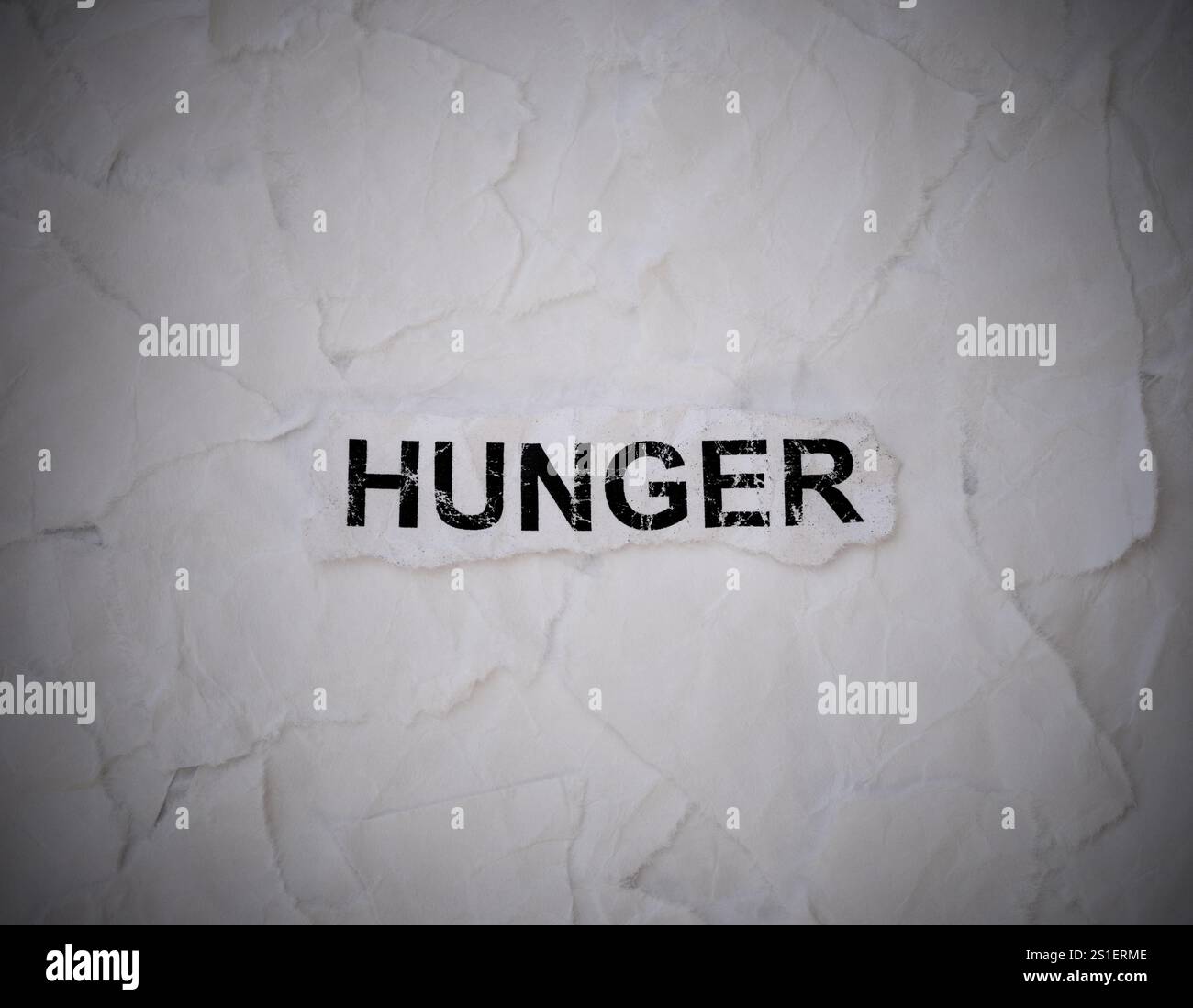 Crumpled piece of paper with word Hunger on torn white paper pieces ...