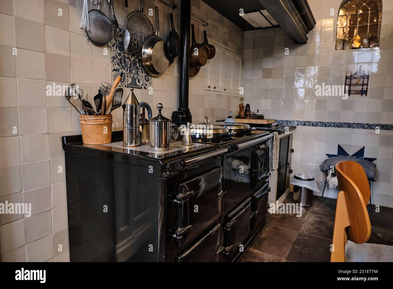 A historic Dutch kitchen featuring a vintage stove, hanging utensils ...