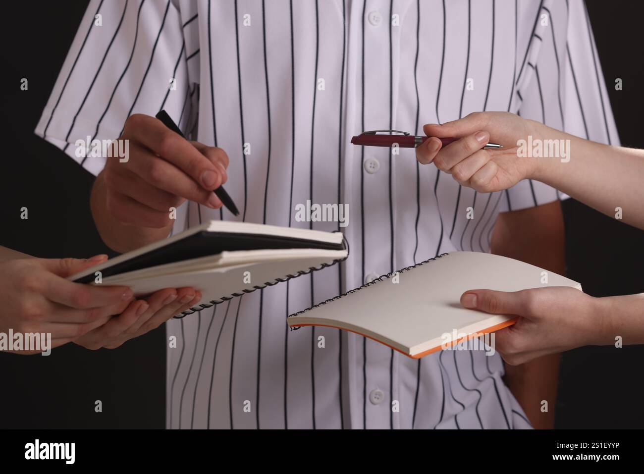 Baseball player signing autograph in notebook against black background ...