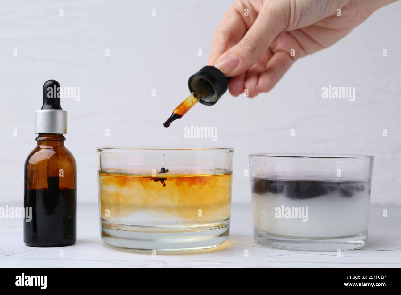 Iodine starch test. Woman dripping iodine into glass of water at white ...