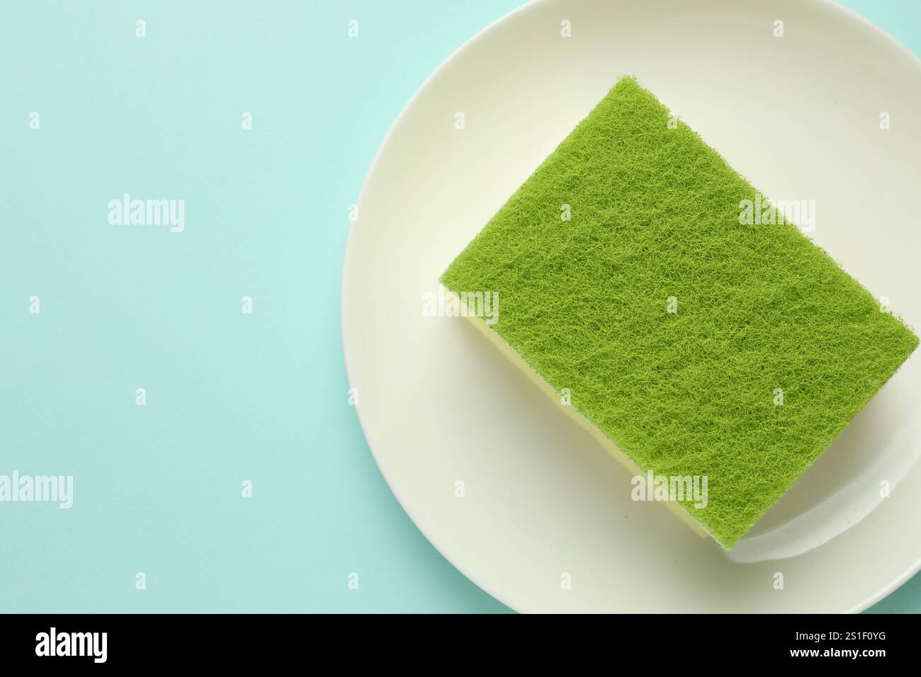 One sponge and plate on light blue background, top view. Space for text ...
