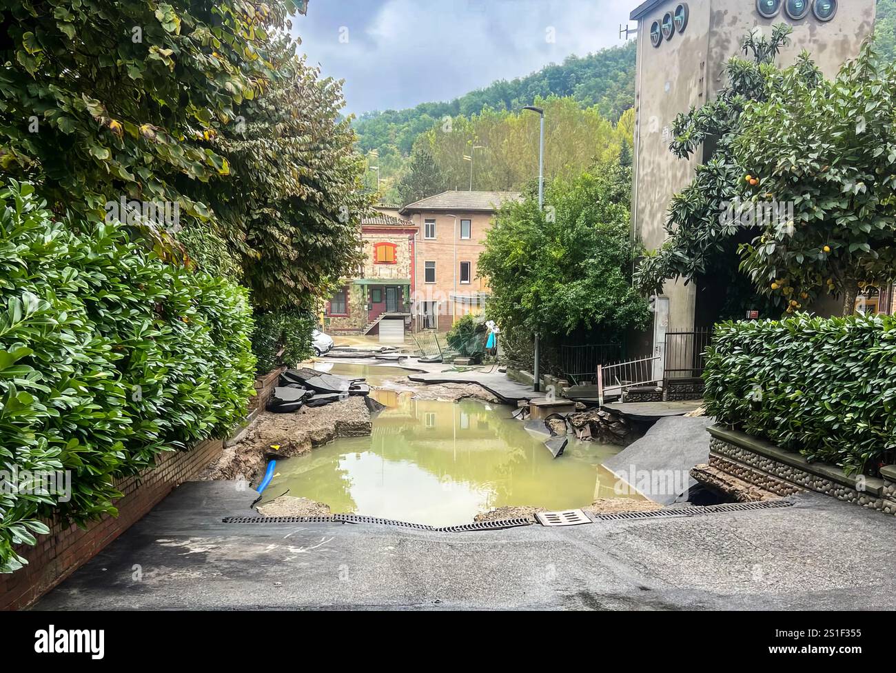 Urban flooding aftermath with damaged road and standing water. A ...
