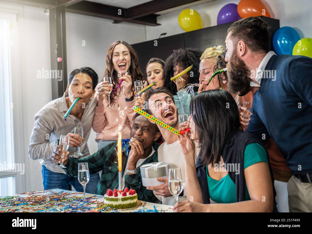Group of friends celebrating a birthday with a sparkling cake and party ...