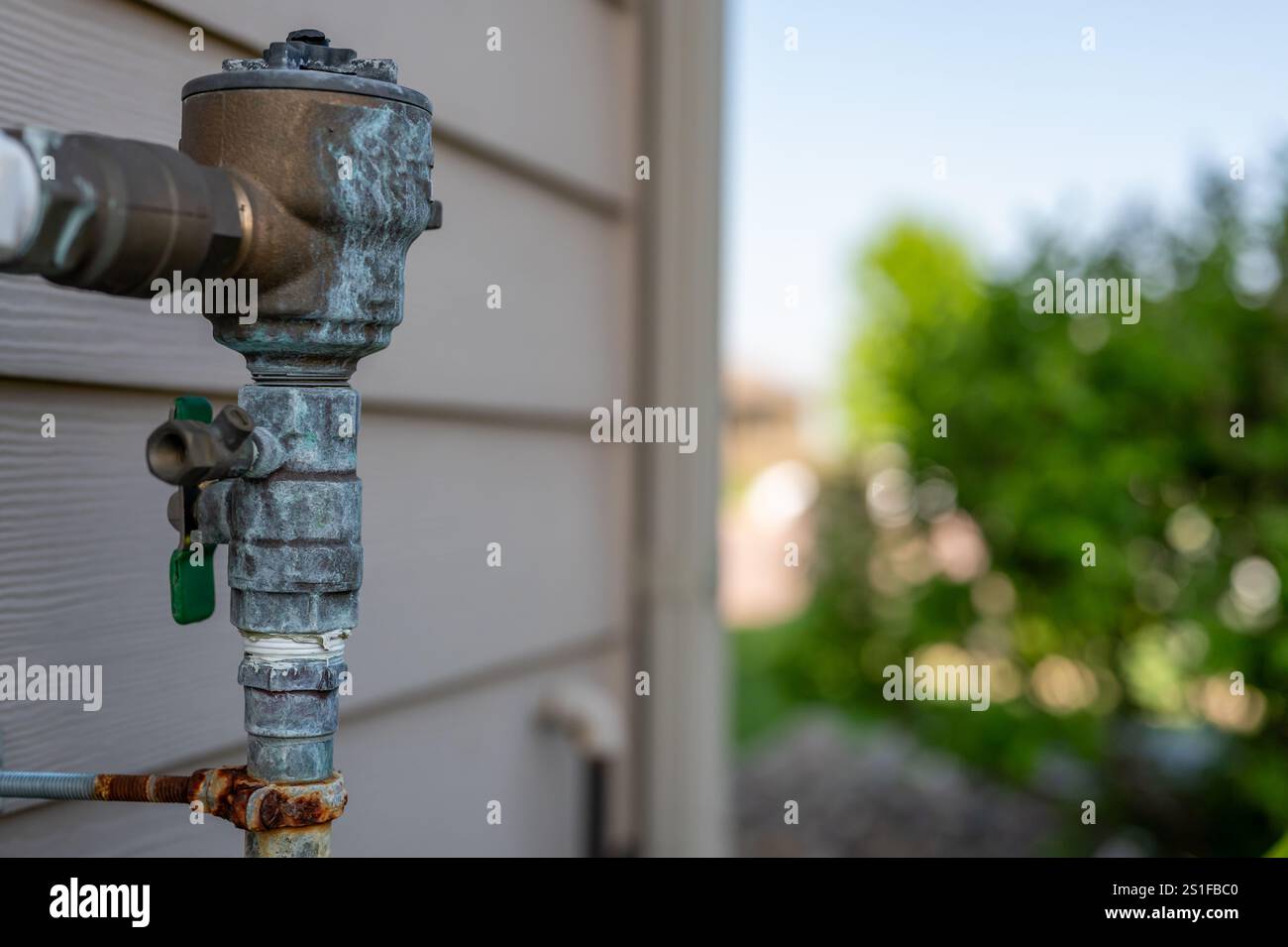 Rusted outdoor water sprinkler backflow preventer on the side of a ...