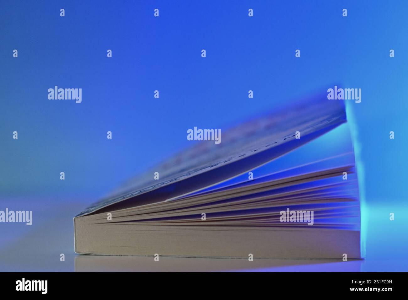 Slightly open book against a blue background Stock Photo - Alamy