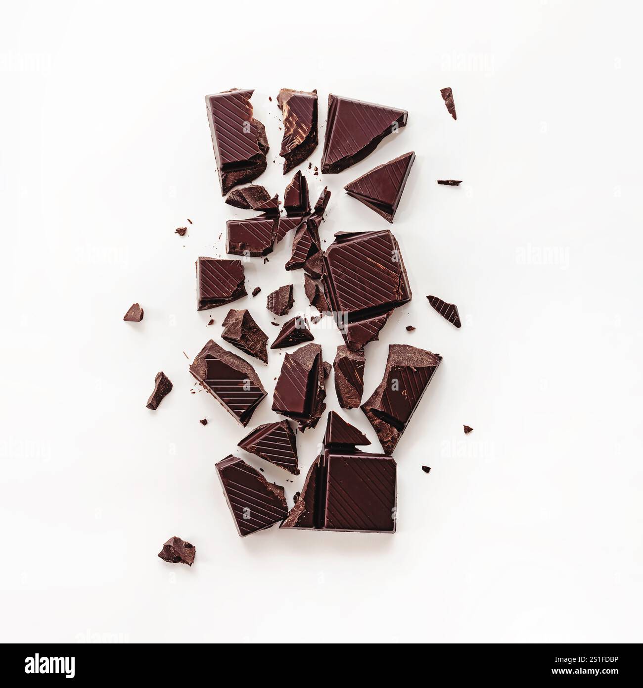 Dark chocolate chunks are broken and scattered over a plain white ...