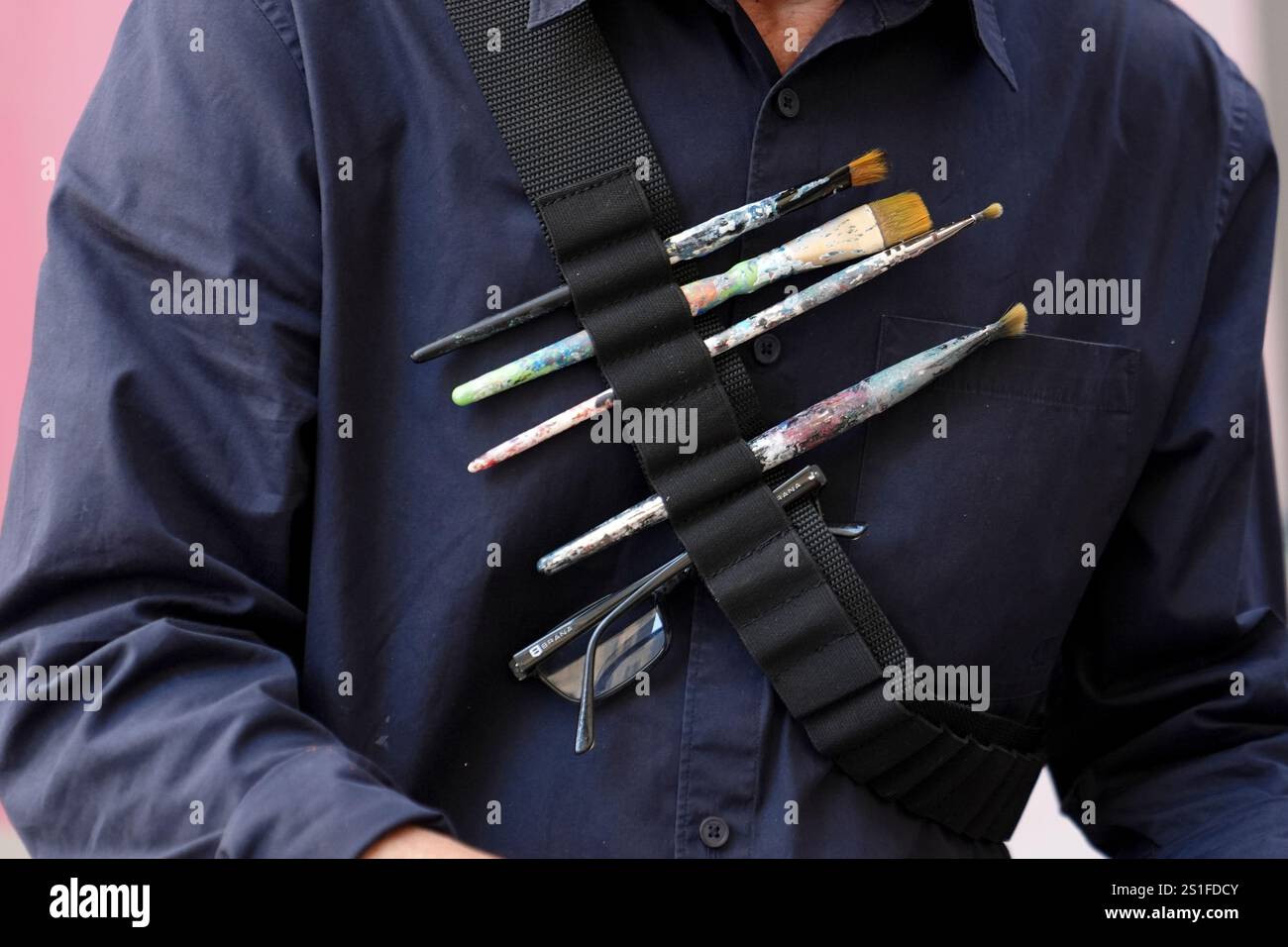Roberto Marquez wears brushes on his chest as he paints a mural at a ...