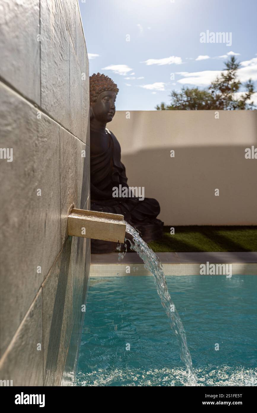 Close-up of a modern outdoor fountain pouring water into a pool, with a ...