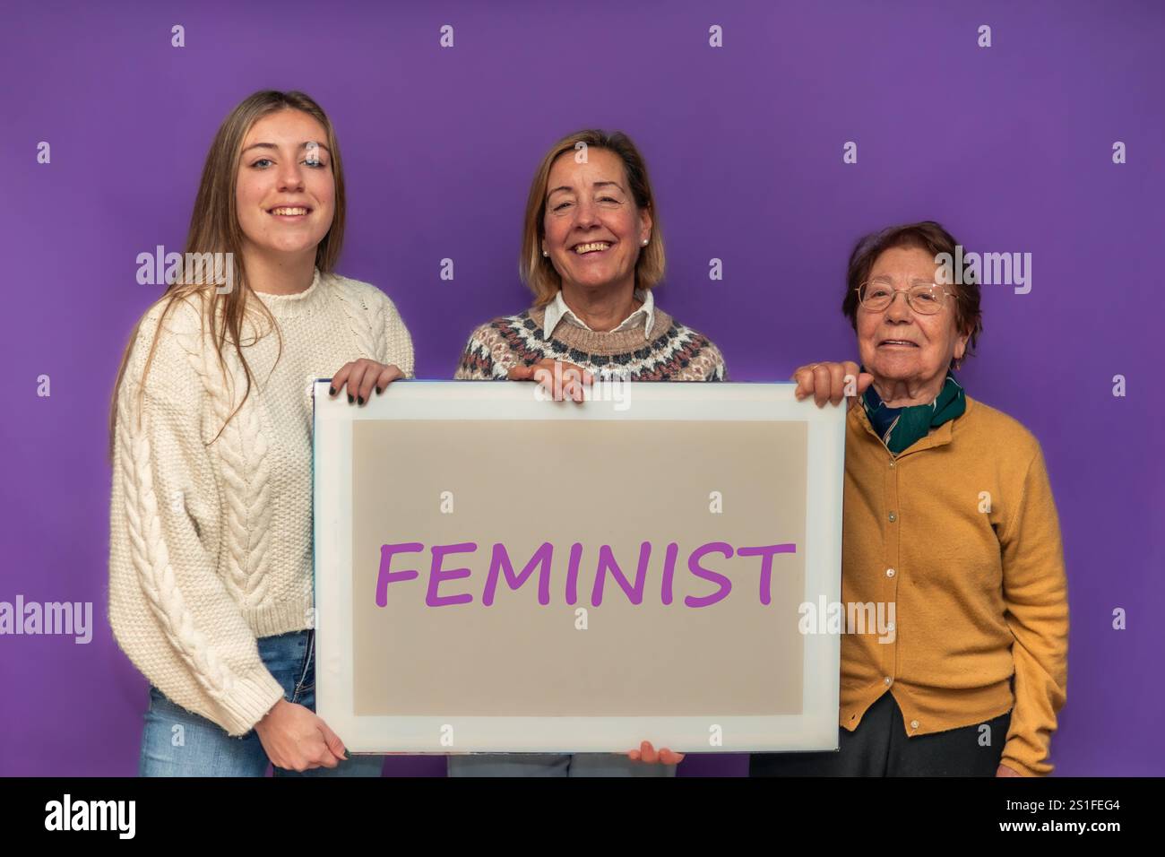 Grandmother, mother and daughter holding a sign with the word feminist ...