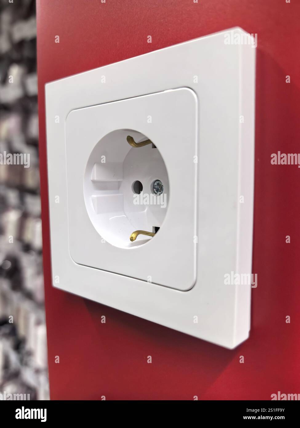 A white electrical outlet is mounted on a bright red wall, surrounded ...