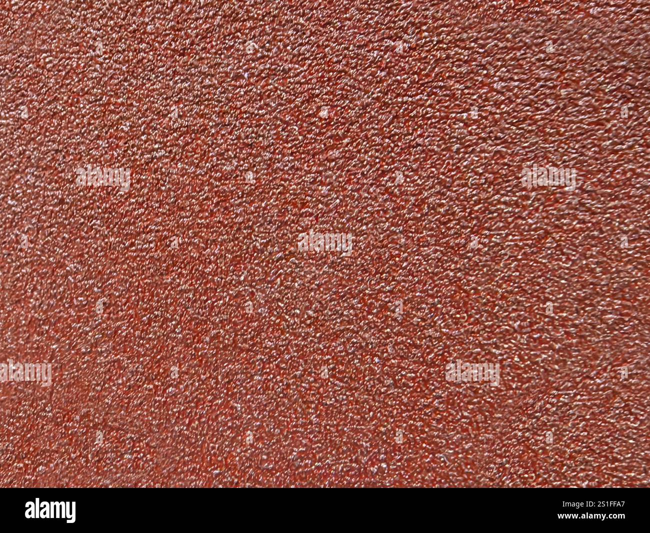 A close-up view shows a textured wall, showcasing an earthy red tone ...