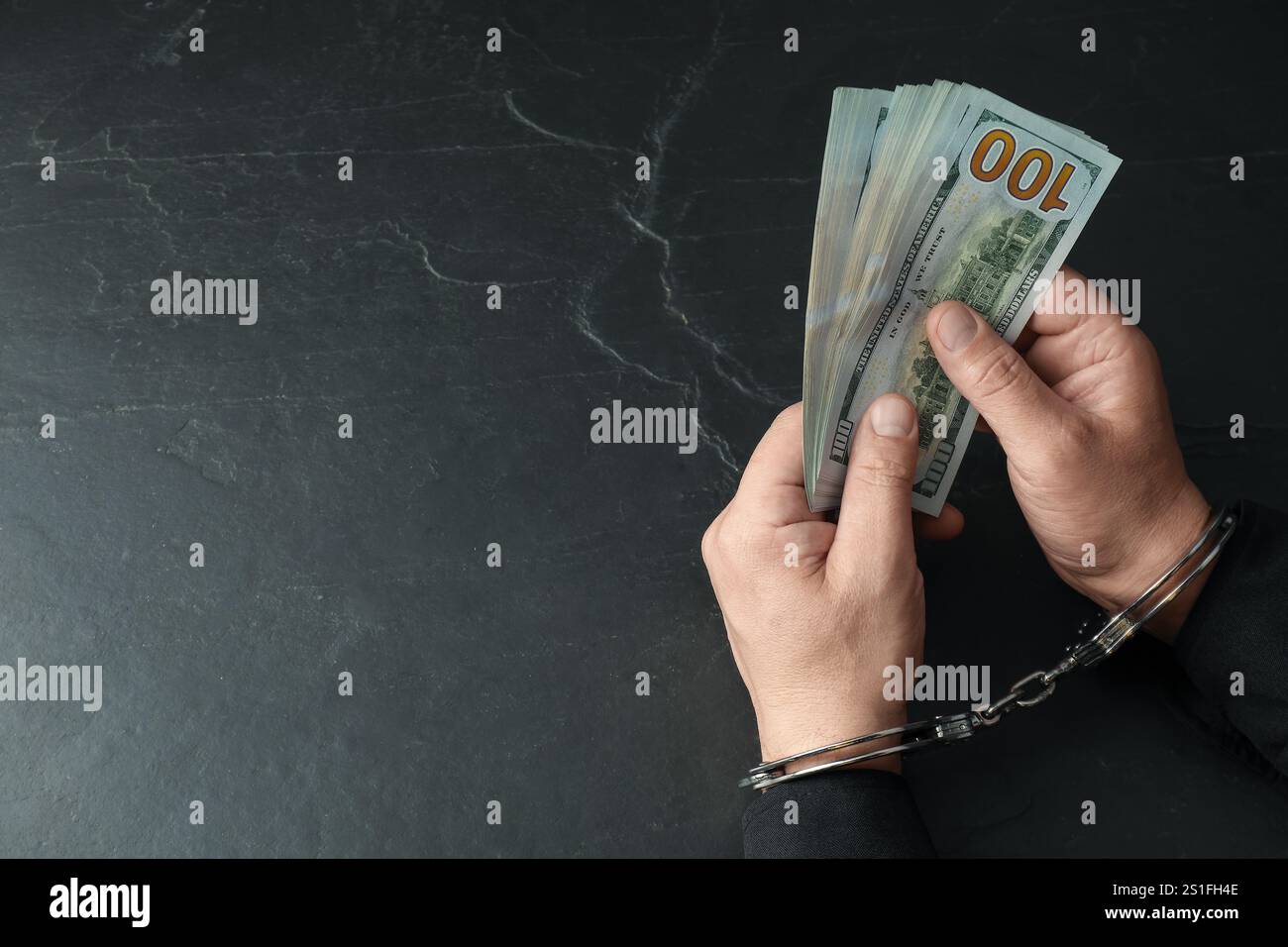 Corruption. Man in handcuffs with dollar banknotes at grey textured ...