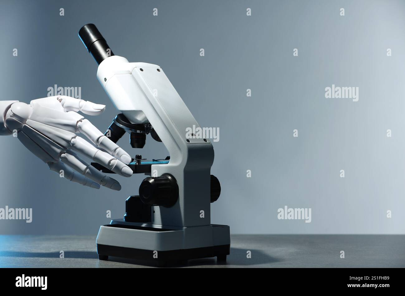 Artificial intelligence. Robot hand working with microscope at table ...