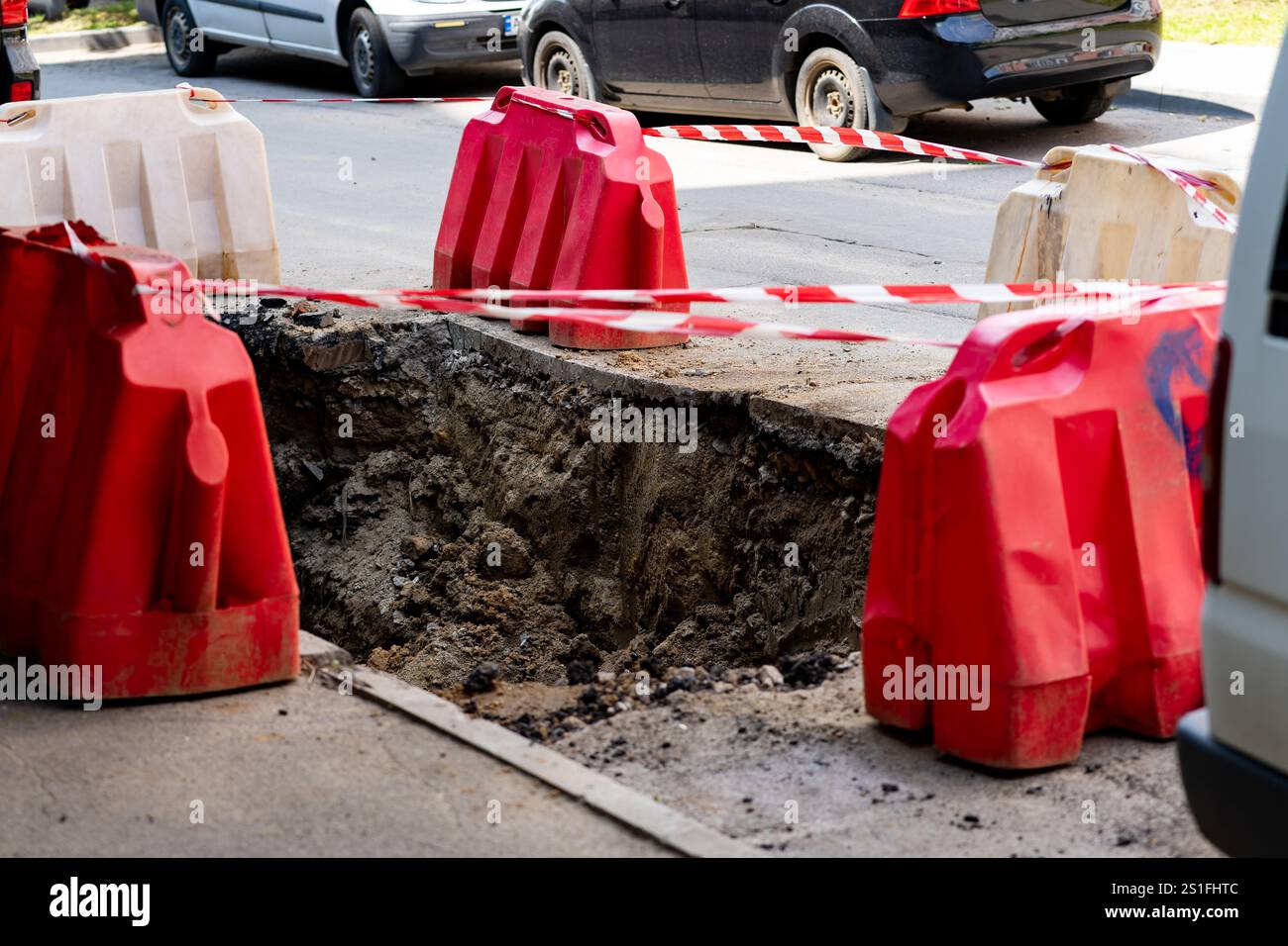 A deep excavation site is blocked off by bright red barriers, warning ...