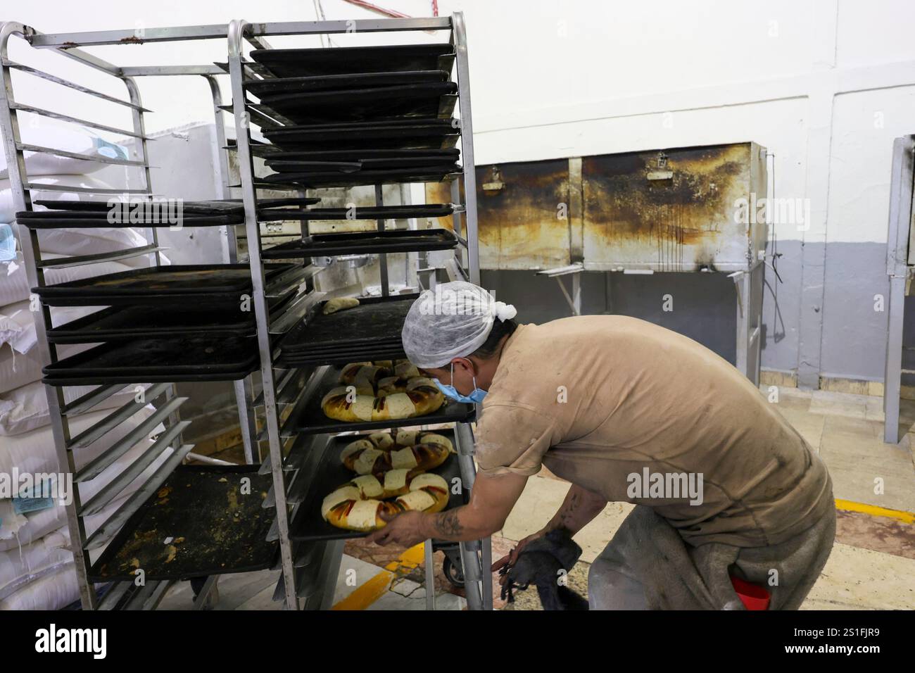 An inmate slides a king cake, or "rosca," onto a rack as he and other ...