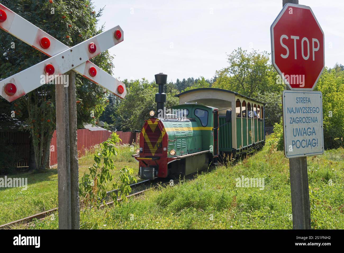 A green train at a level crossing with stop sign and warning signs ...