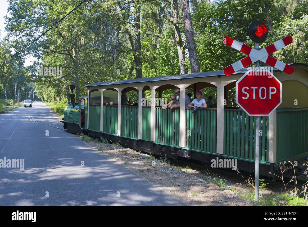 A train crosses a road with a stop sign. People look out of the windows ...