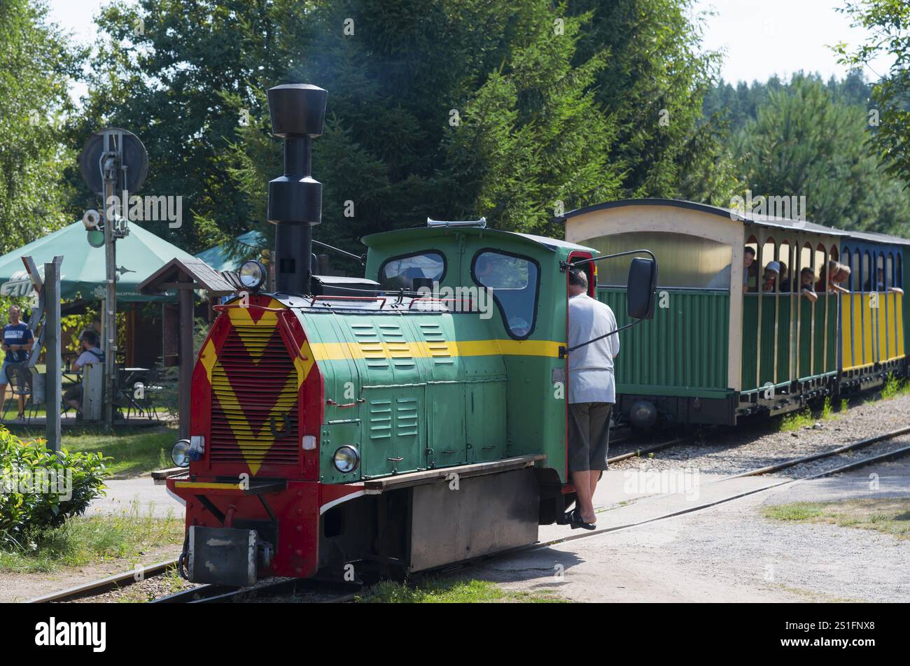 A train with people in the wagon stands at a small, rural railway ...