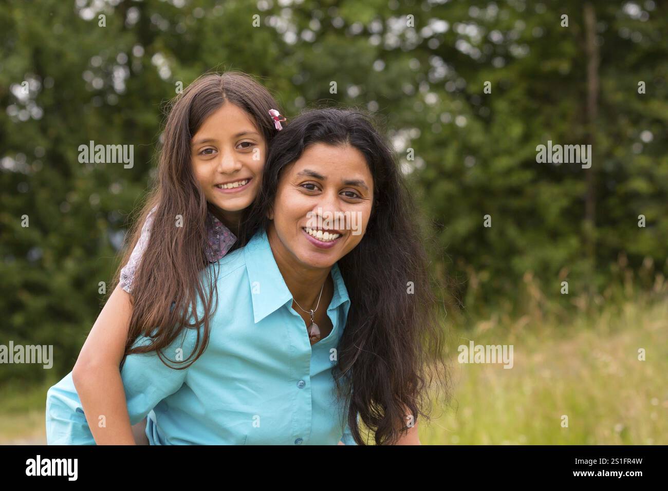 Woman carrying child piggyback in the meadow in summer Stock Photo - Alamy