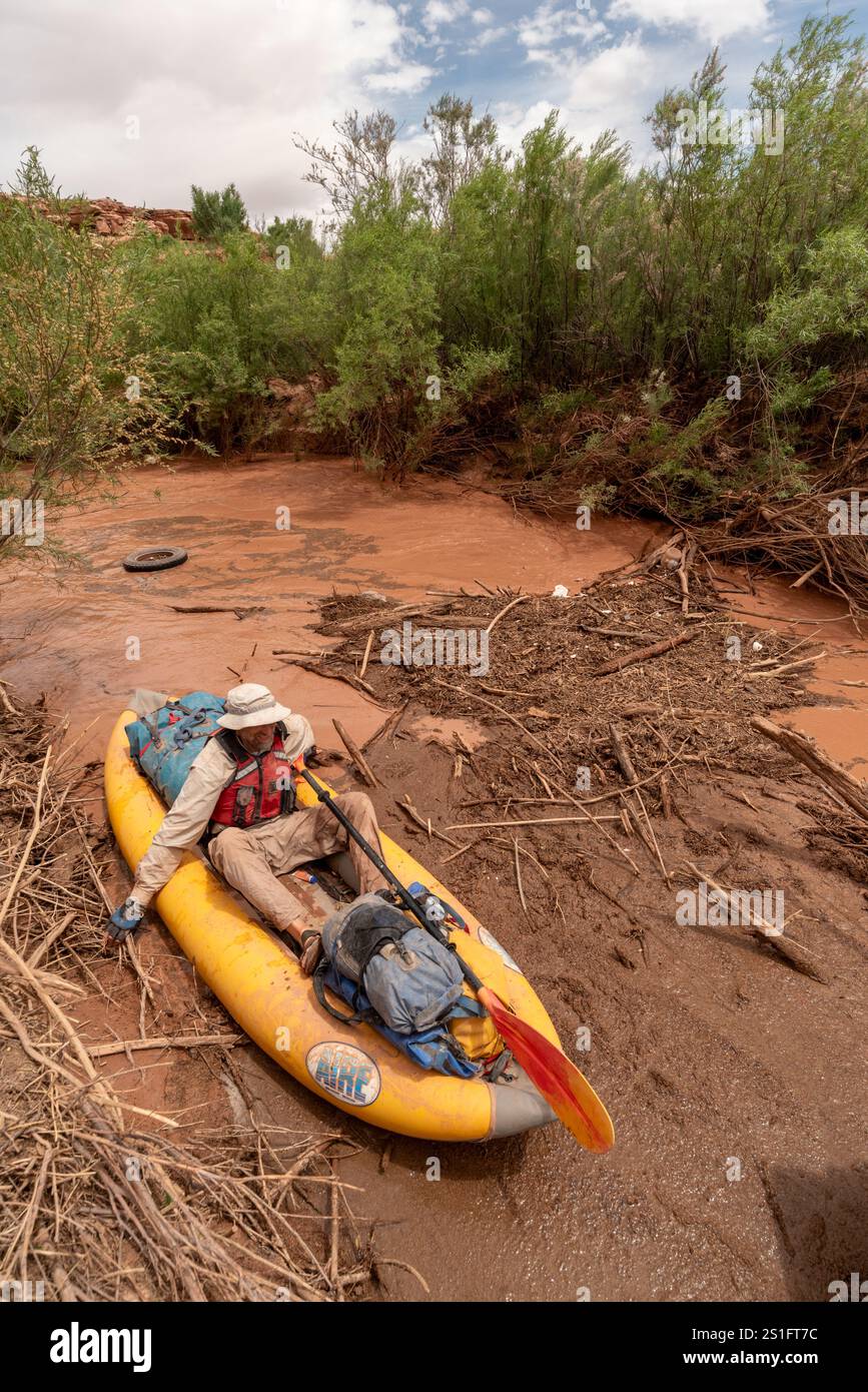 Boater navigating through flood debris on a stream in Northern Arizon ...