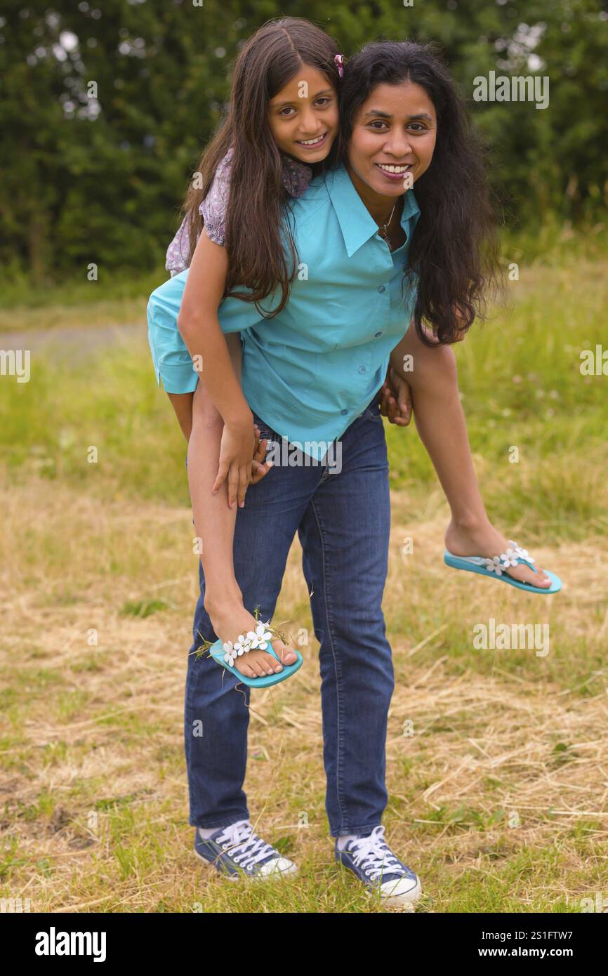 Woman carrying child piggyback in the meadow in summer Stock Photo - Alamy
