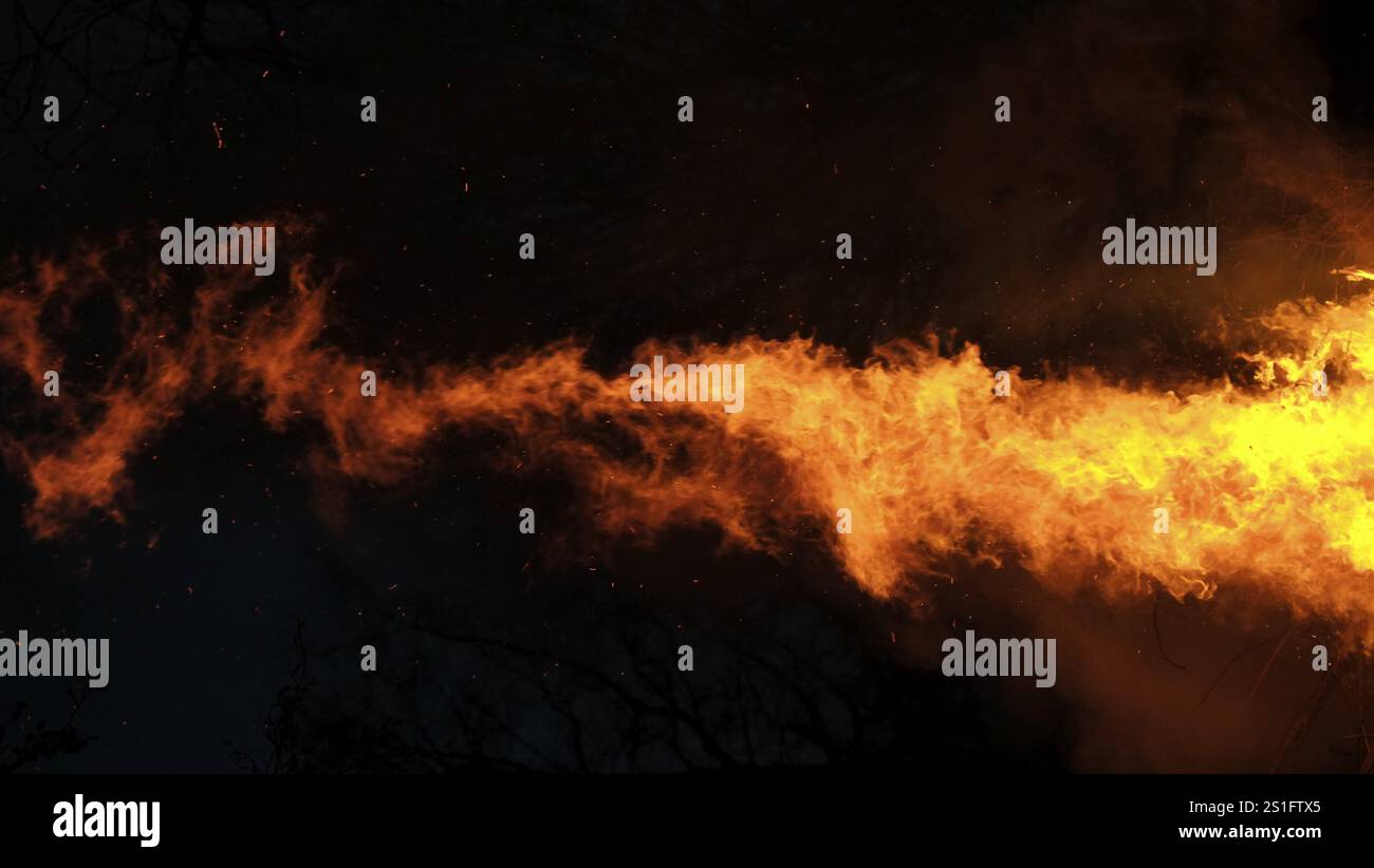 Flames form a horizontal tail of fire against a black background ...