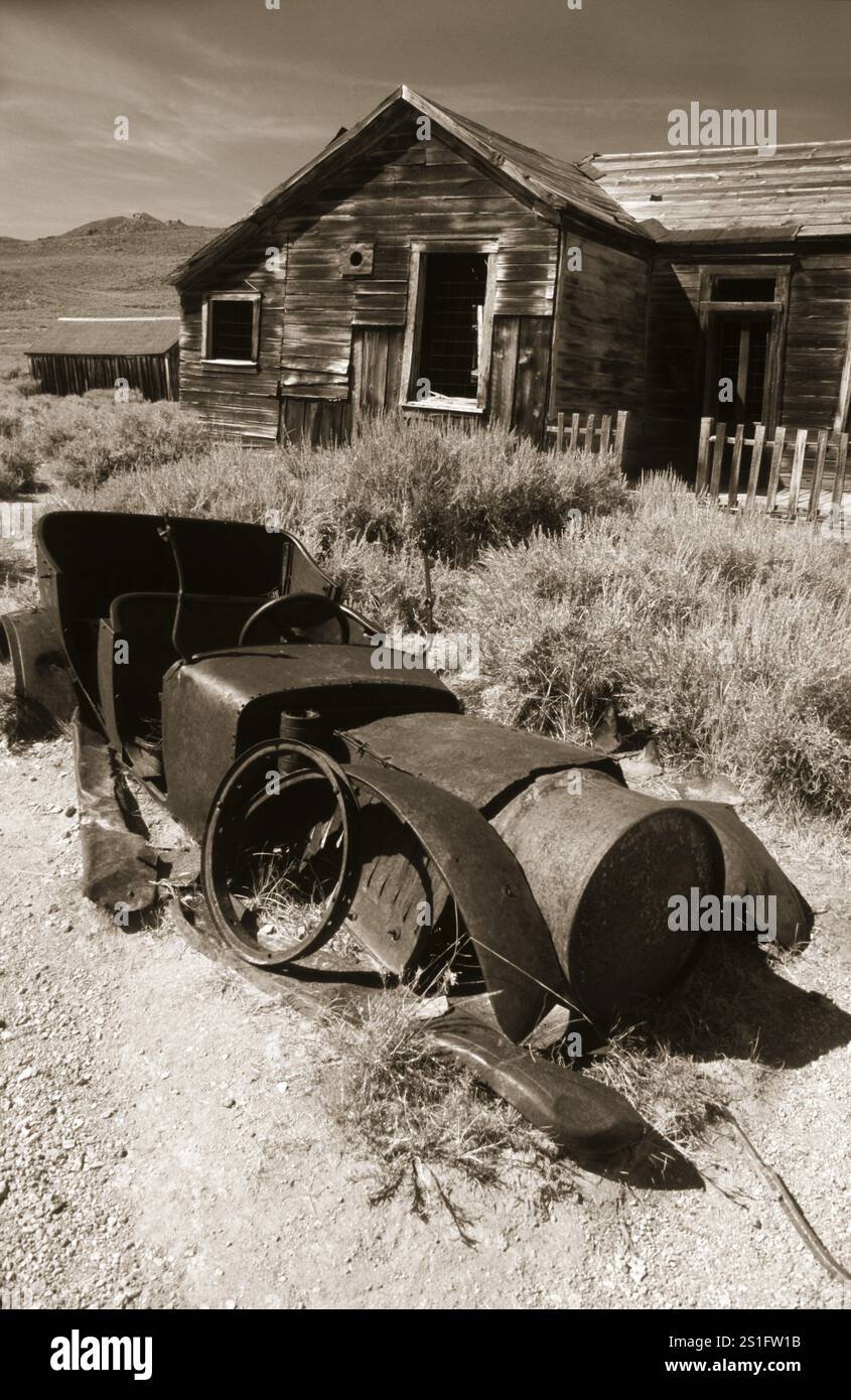 Individual parts of a rusty old car wreck in front of a wooden house in ...