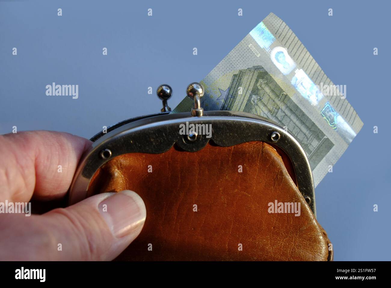 Thumb and forefinger hold an old-fashioned purse made of brown leather ...