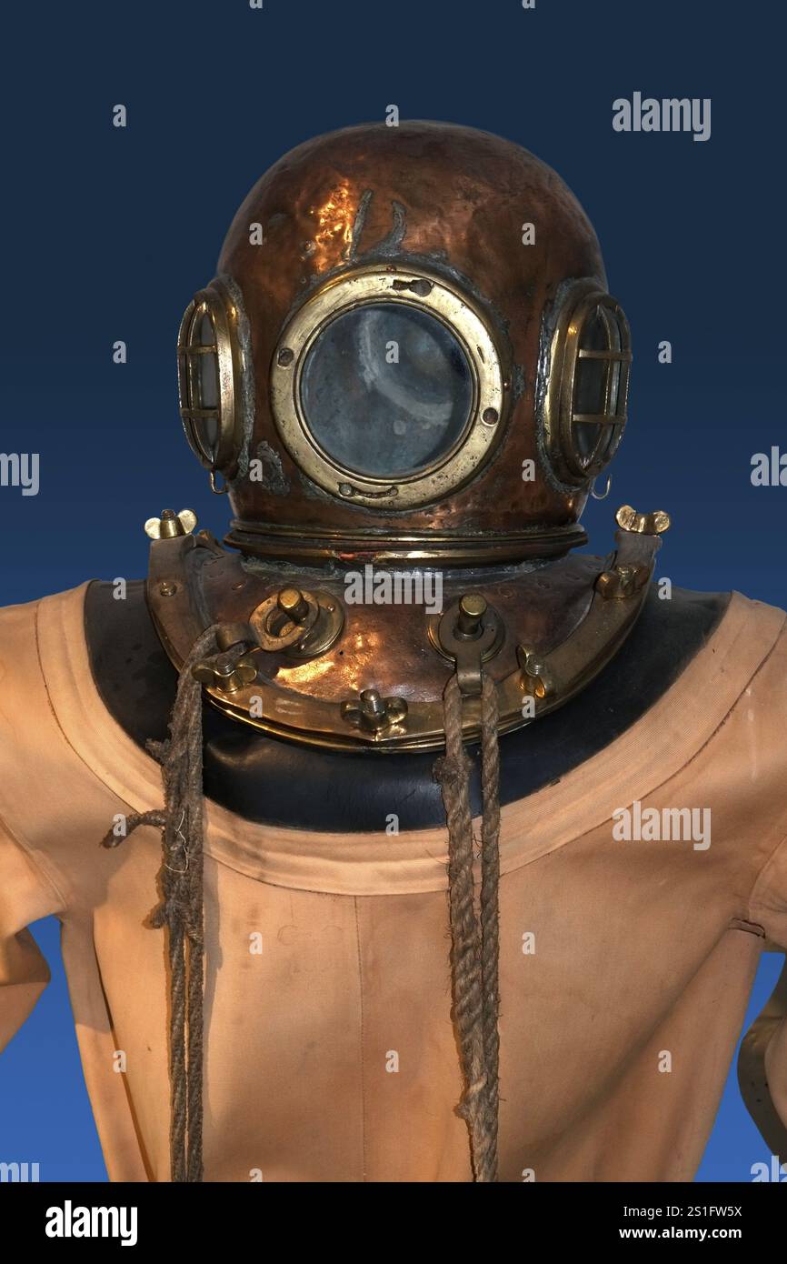 Diving suit and metal diving helmet with round viewing windows against ...