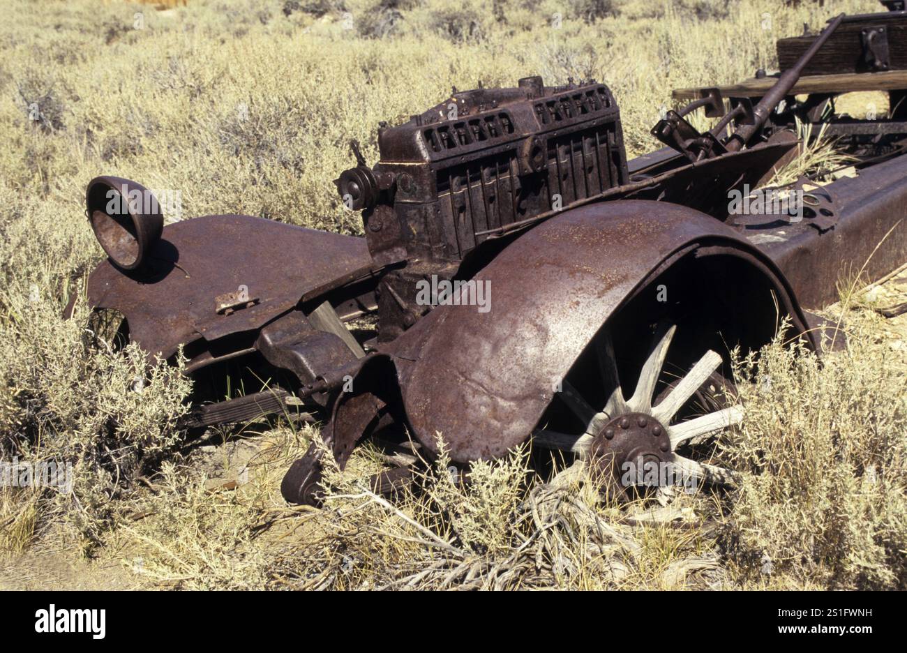 Individual parts of a rusting old car wreck with large mudguards in a ...